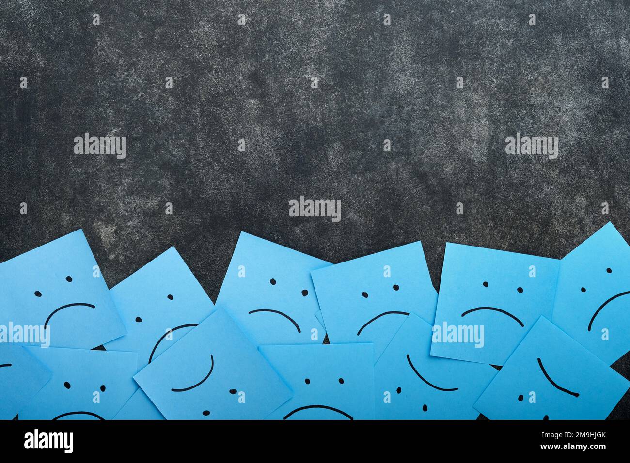 Blue sticky notes blank with drawing sad face on black background with ...