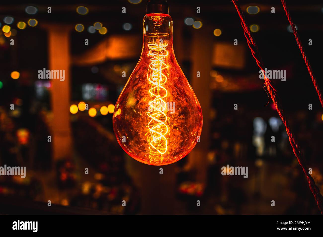 A closeup of a big lit light bulb with its spiral visible against ...