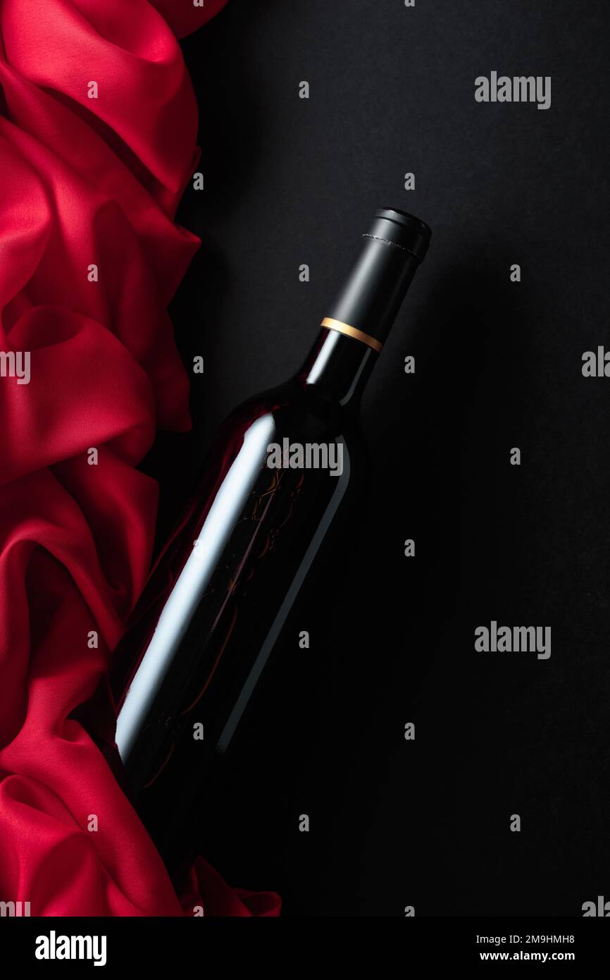 Bottle of red wine with red satin on a black background. Top view Stock ...