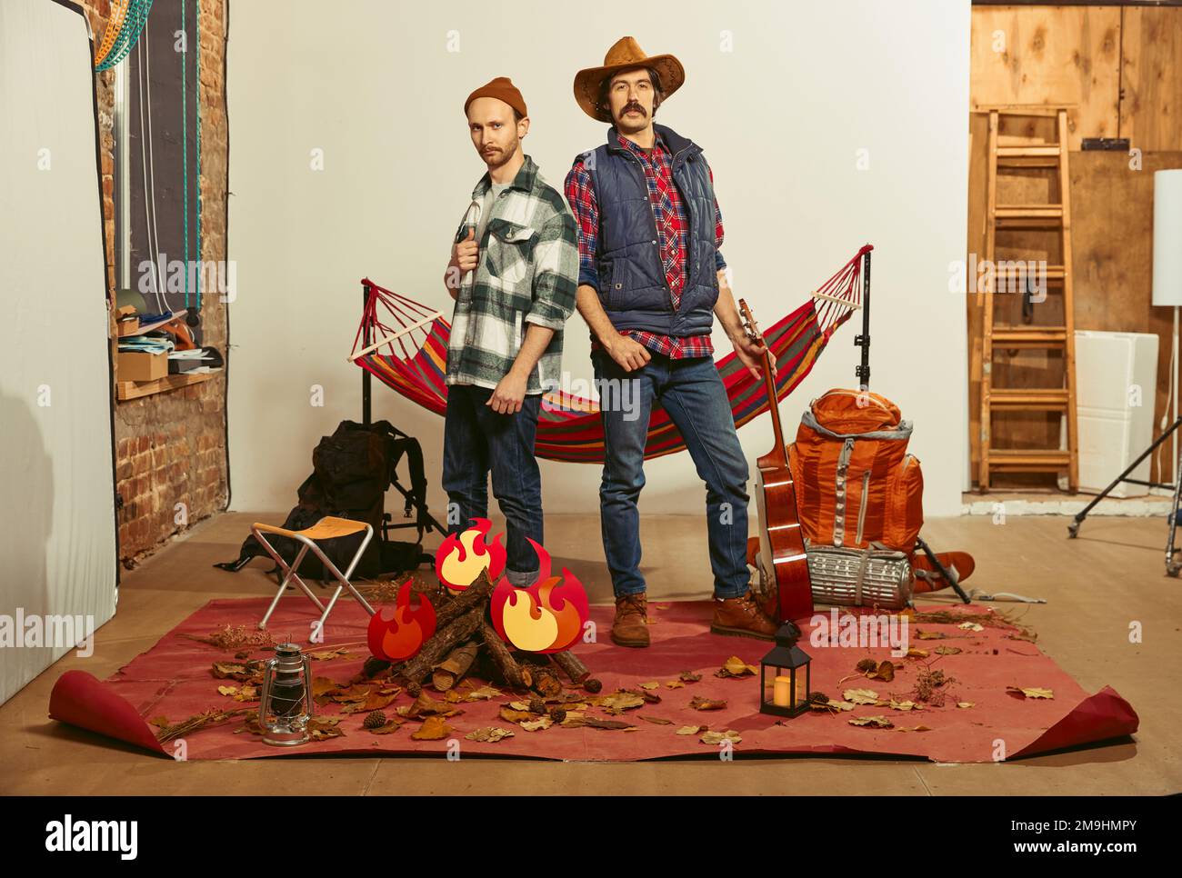 Friends, team. Two men imagining, recreating camping activity indoors ...