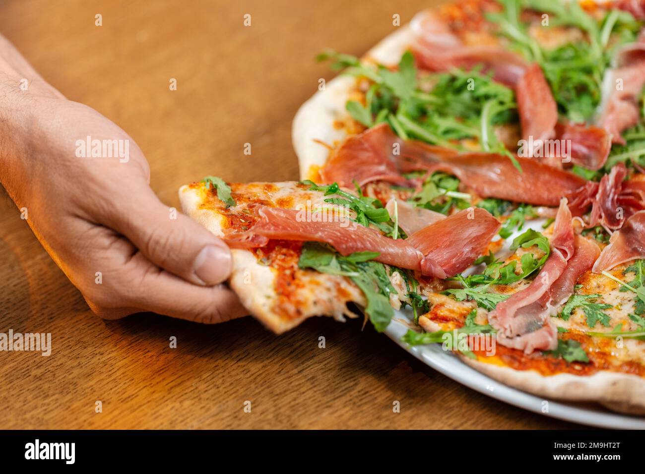 close up of hand taking pizza slice from plate Stock Photo - Alamy