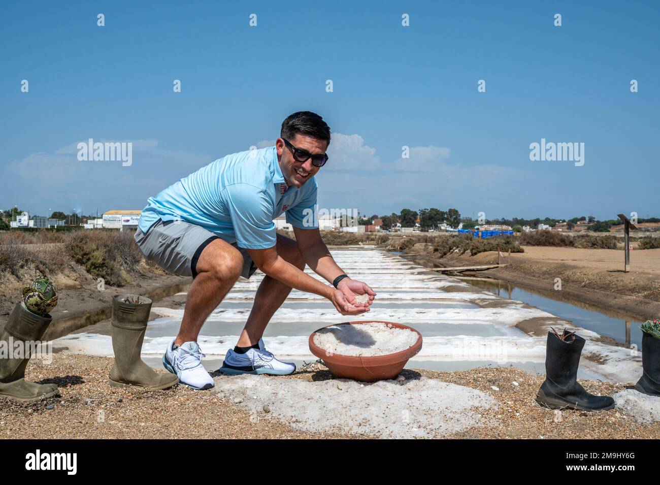 Man holding handful of salt from bowl at salt marshes, Isla Cristina ...