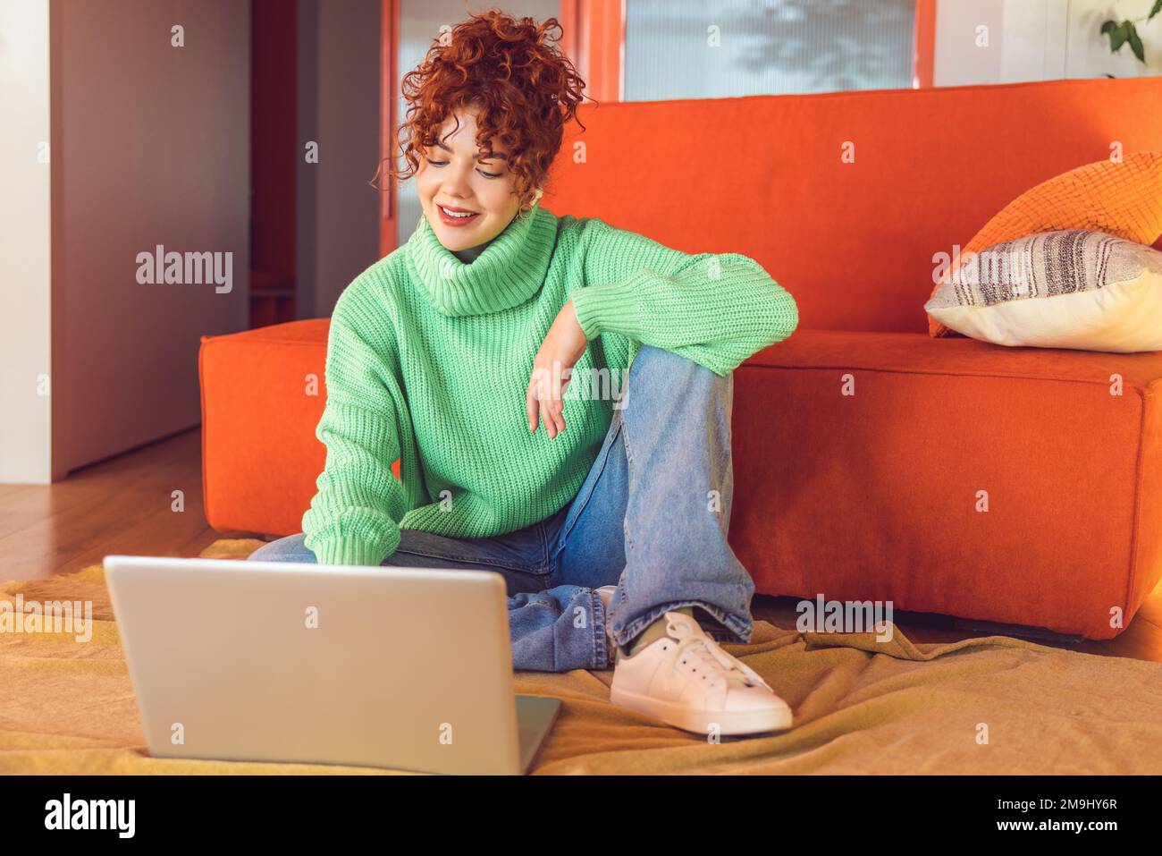 Ginger girl in green sweater sitting on the floor at the laptop Stock ...