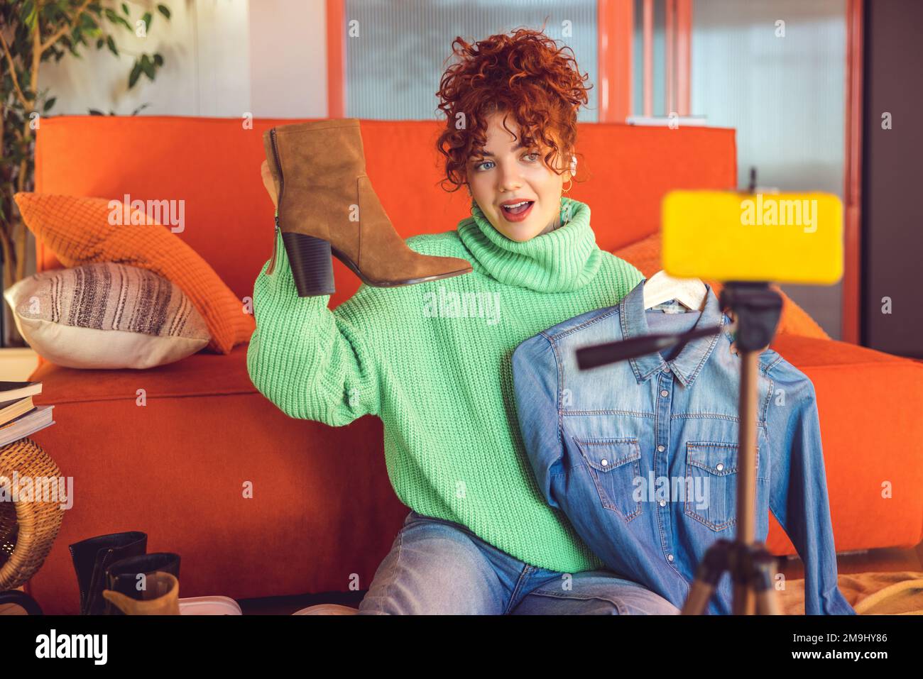 Ginger young girl demonstrating and selling clothes online Stock Photo ...