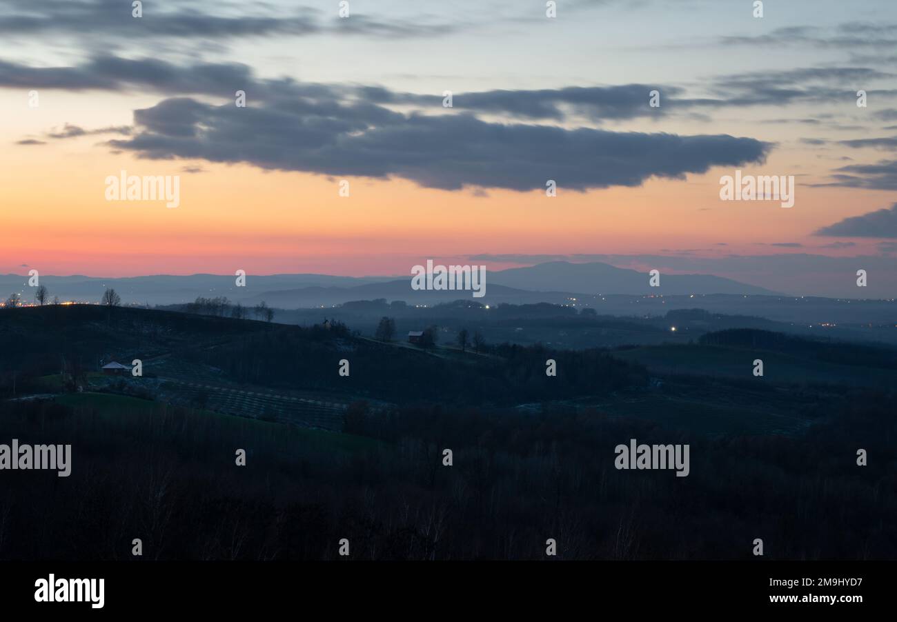 Hilly village against mountain silhouette at twilight, peaceful rural ...