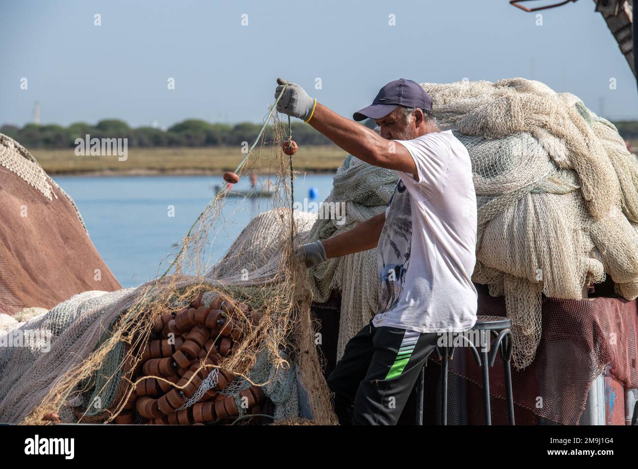 Man untangling fishing nets on dock, Fishing port, Punta Umbria, Spain ...