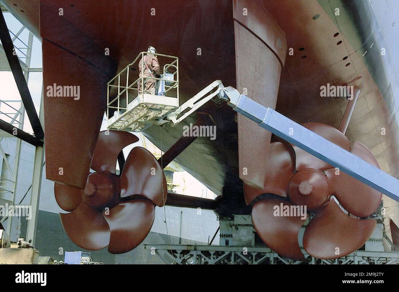 Low-angle Stern on view showing a shipyard worker aboard an extendable ...