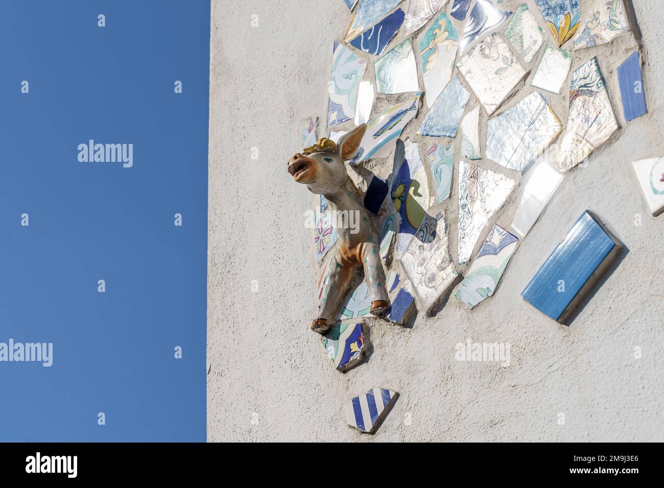 A cow statue coming out of a wall of a building during the day in Italy ...