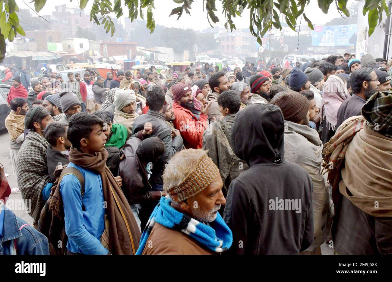 A large numbers of poor people are gathered in a queue for food ...