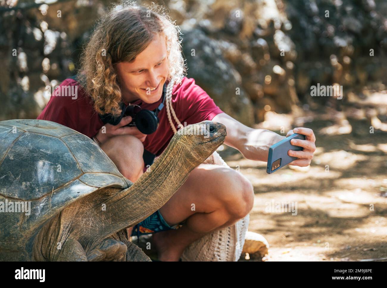 Smiling tourist boy making a selfie using cell phone with Aldabra giant ...