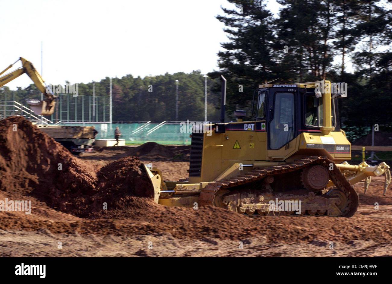 A German contract construction worker uses a bulldozer to excavate dirt ...