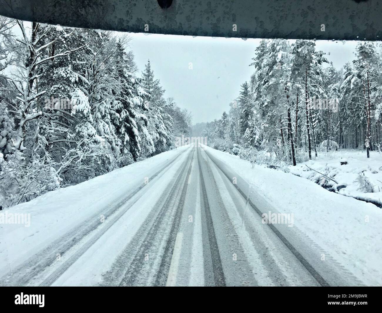 A highway covered in snow and the trails of vehicles on the asphalt ...