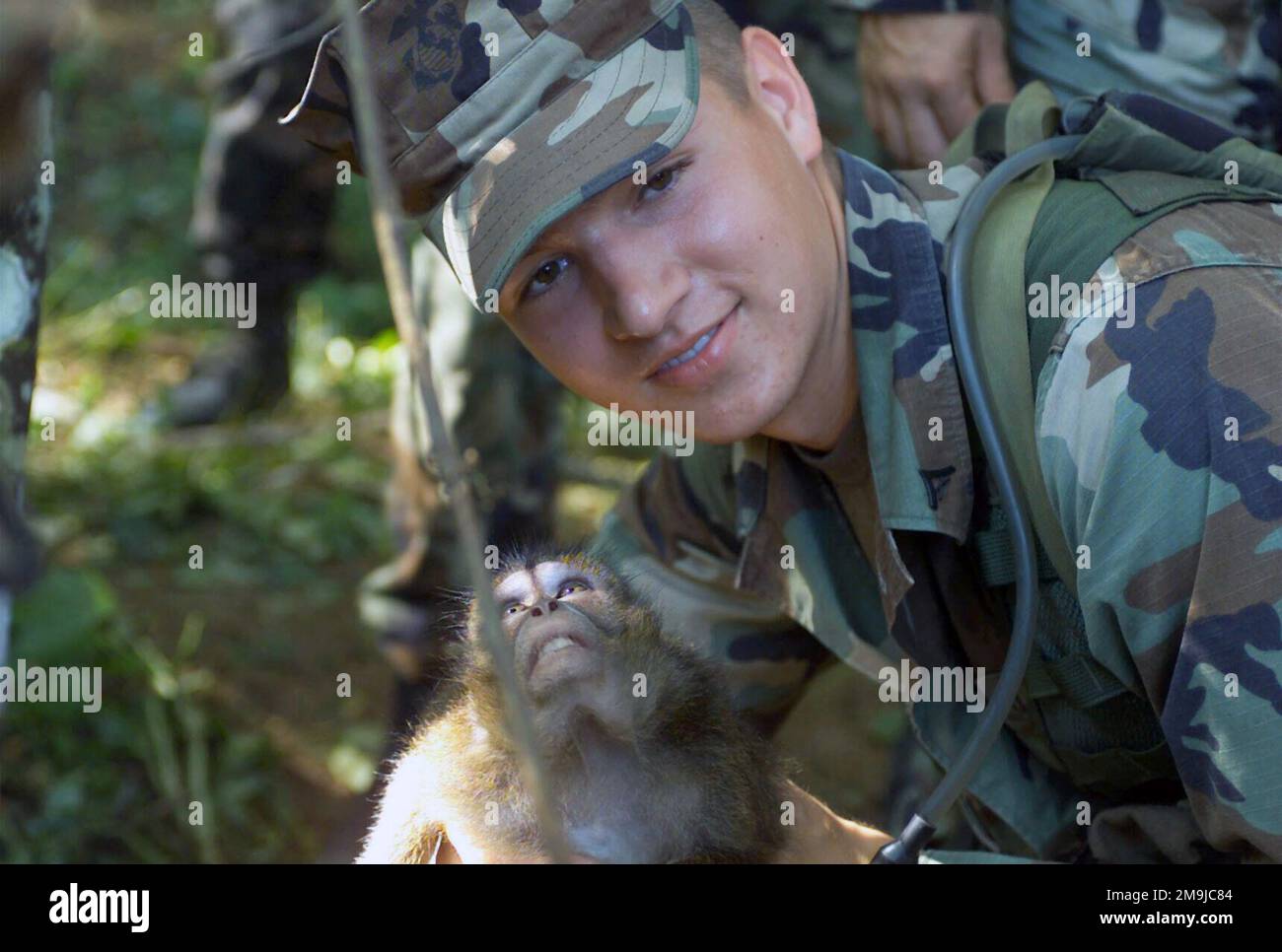 A US Marine Corps (USMC) Marine poses for a photo with wild monkey ...