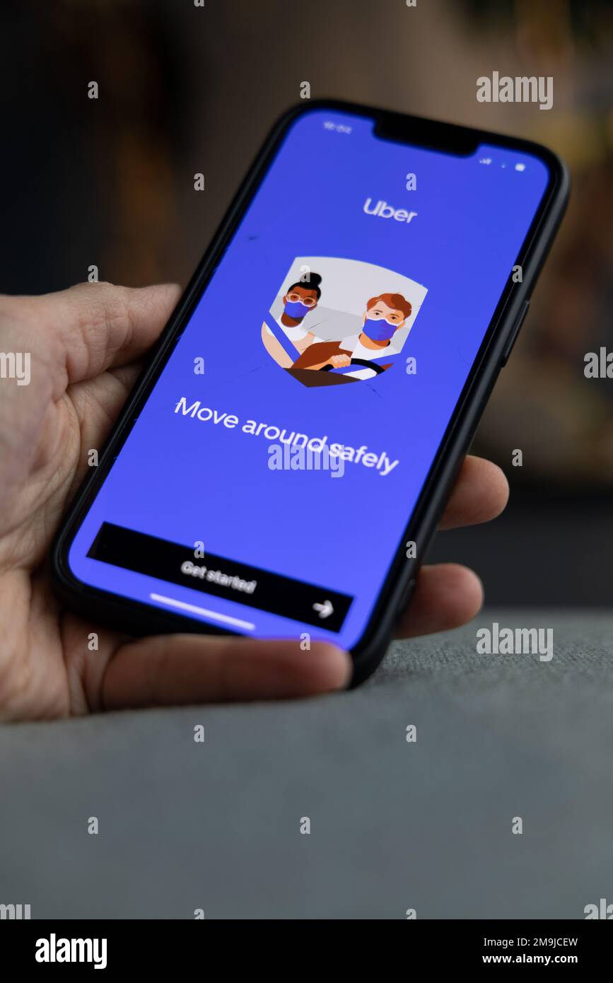 Hand holding a smartphone with Uber icon on screen. Move around safely ...