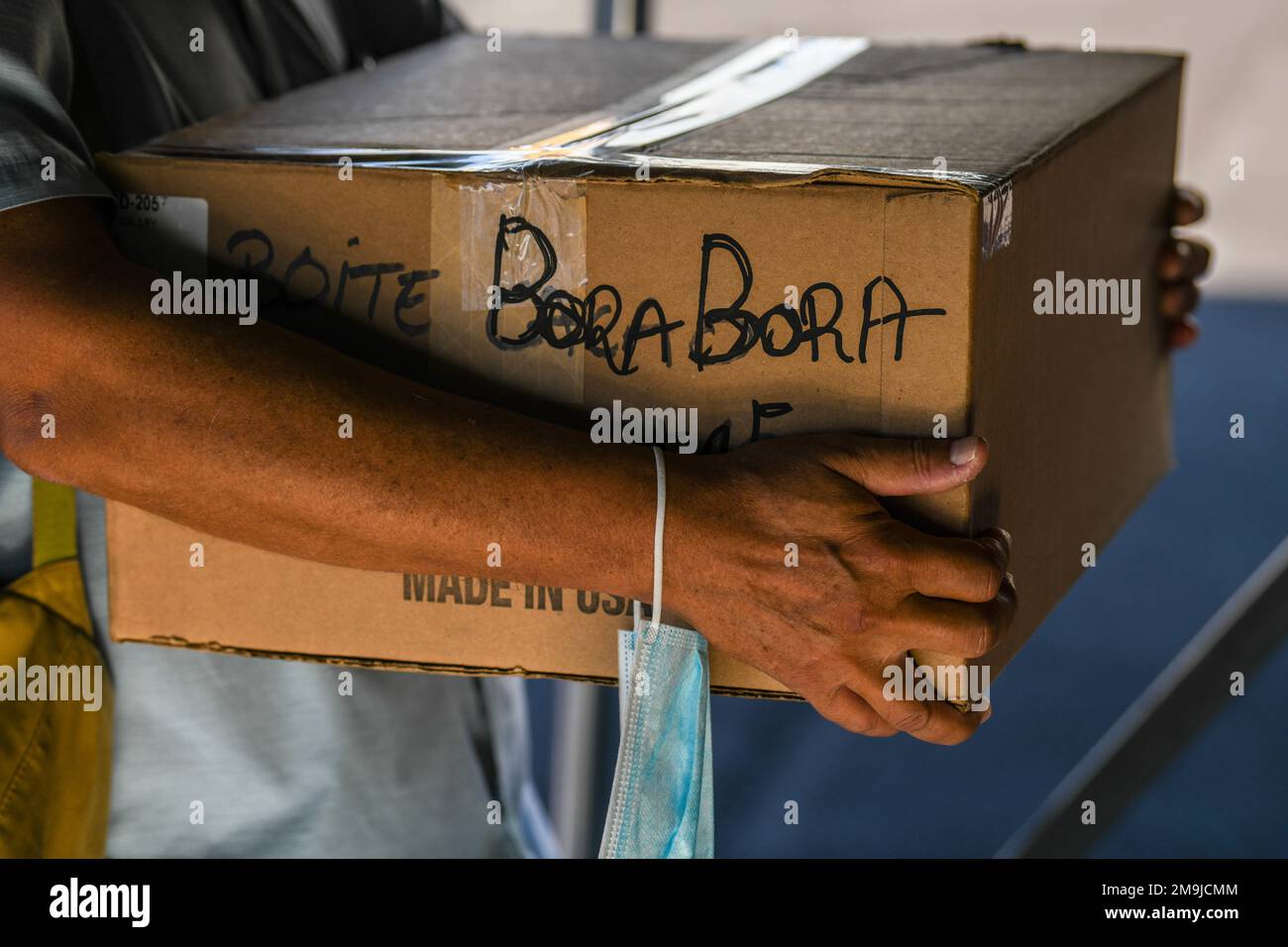 A passenger carrying a box prepares to board a U.S. Air Force C-130J ...