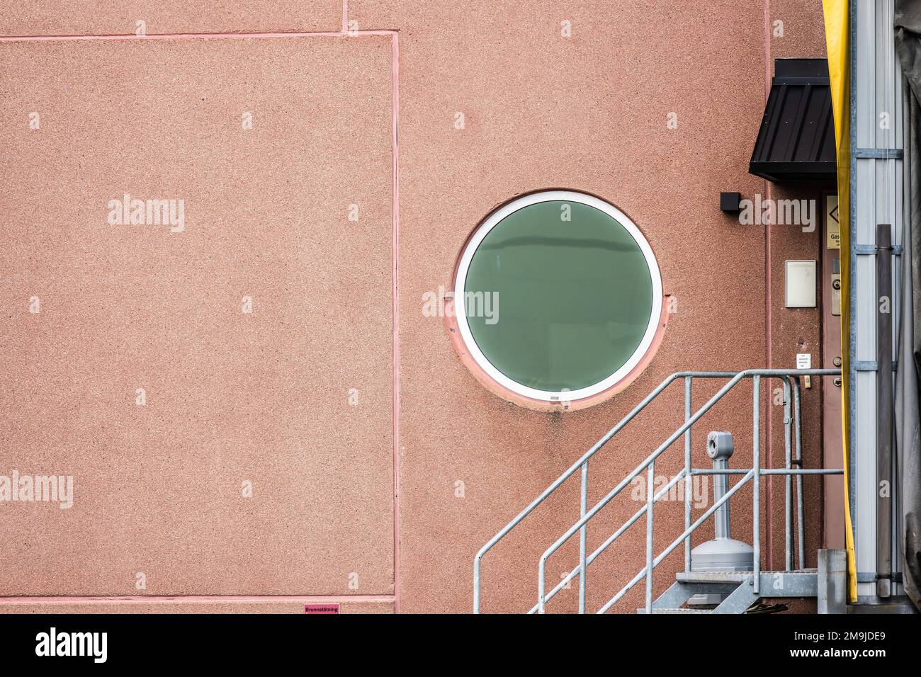 A round glass window on a brown building exterior Stock Photo - Alamy