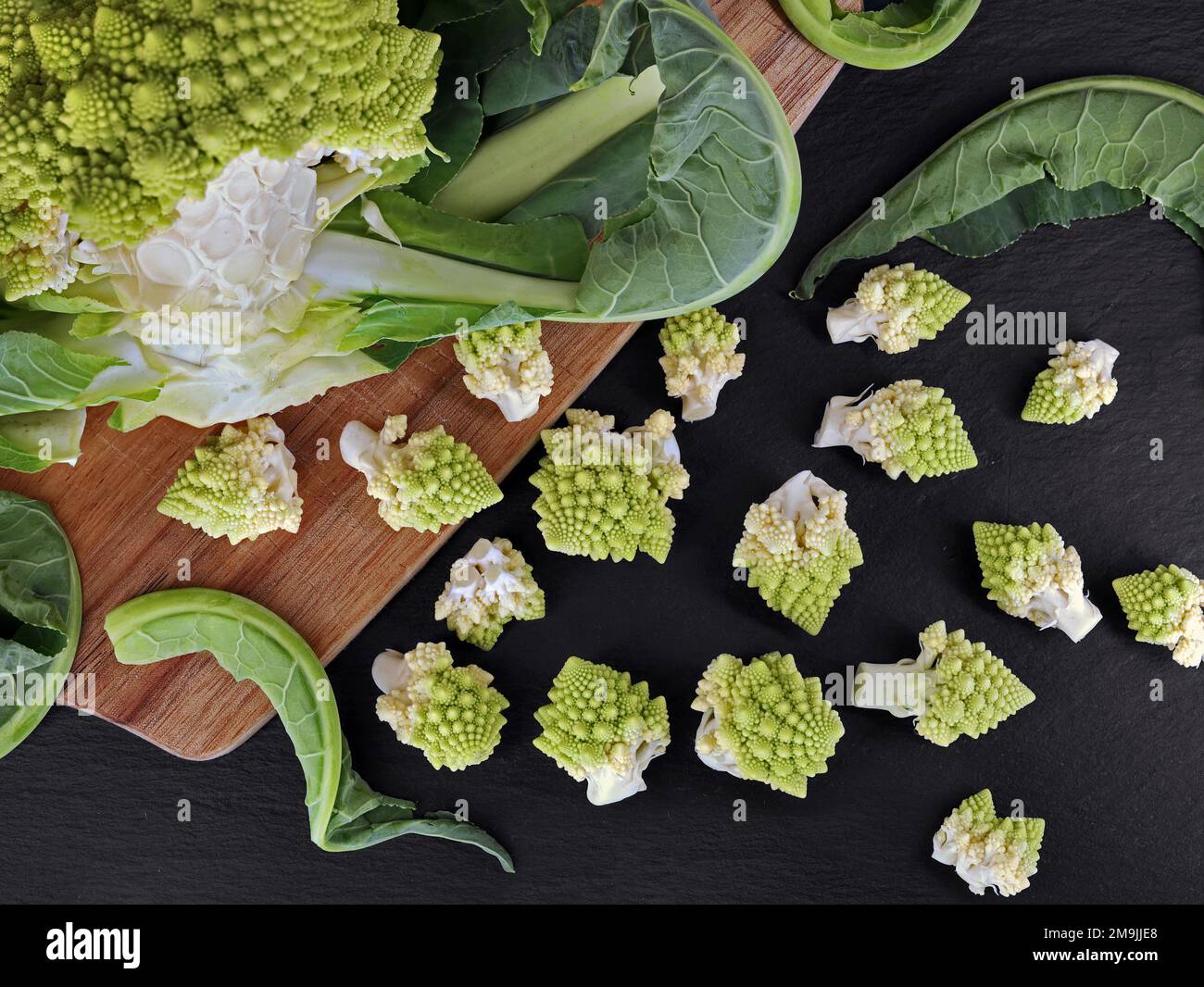 Top view of freshly cut raw romanesco broccoli florets on black slate ...