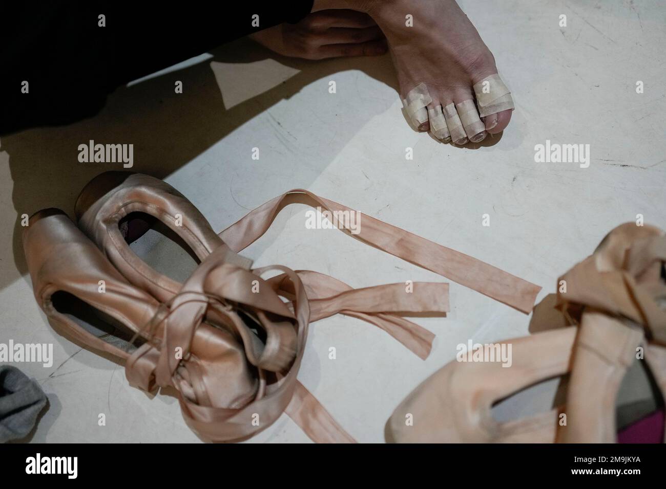 A ballet dancer's toes are wrapped during practice in preparation for ...