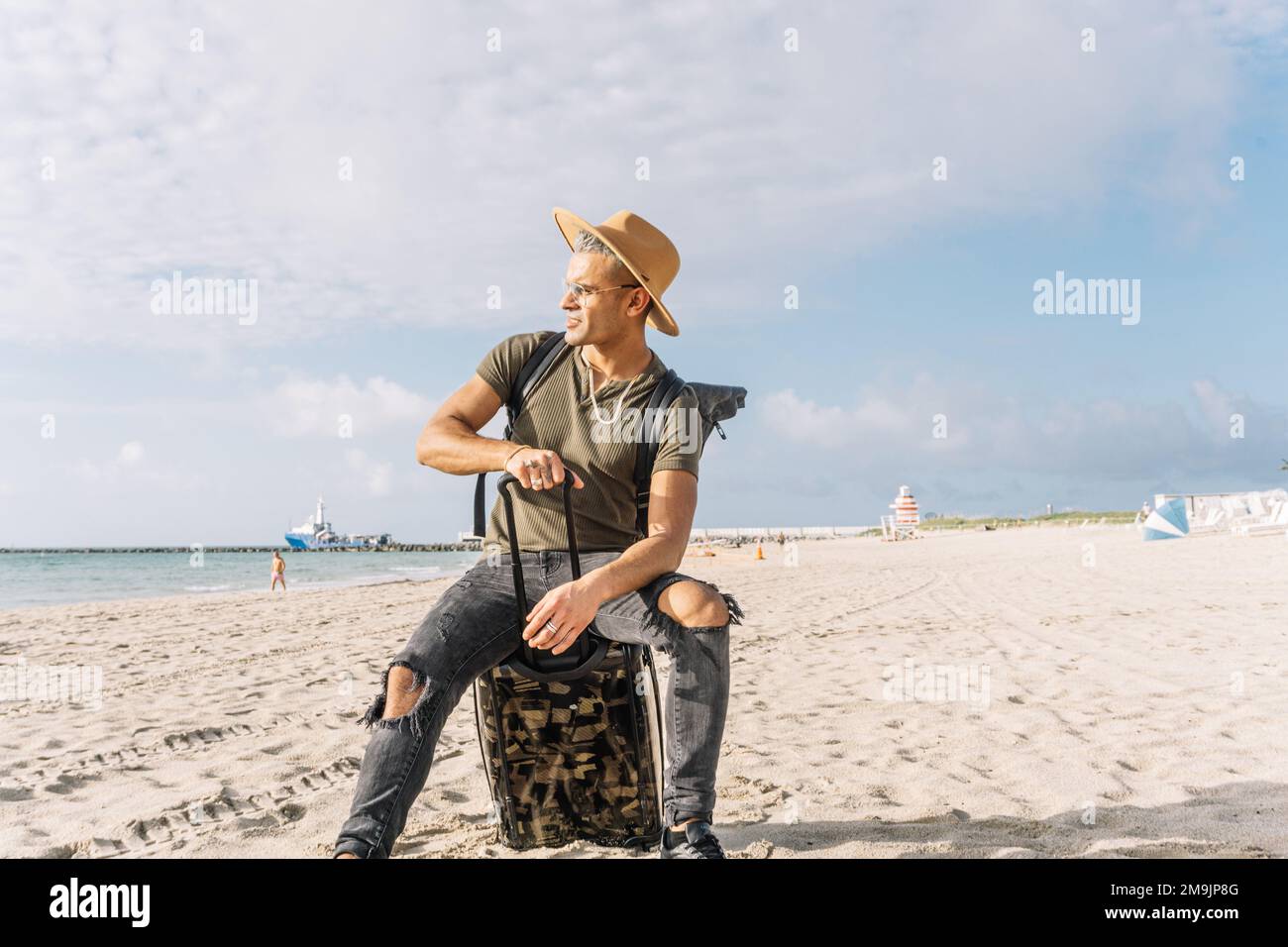 First day of vacation. Handsome man using his carry on luggage as a ...