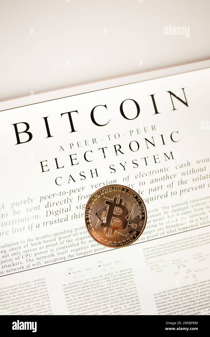 A vertical shot of a Bitcoin lying on a newspaper about cash system ...