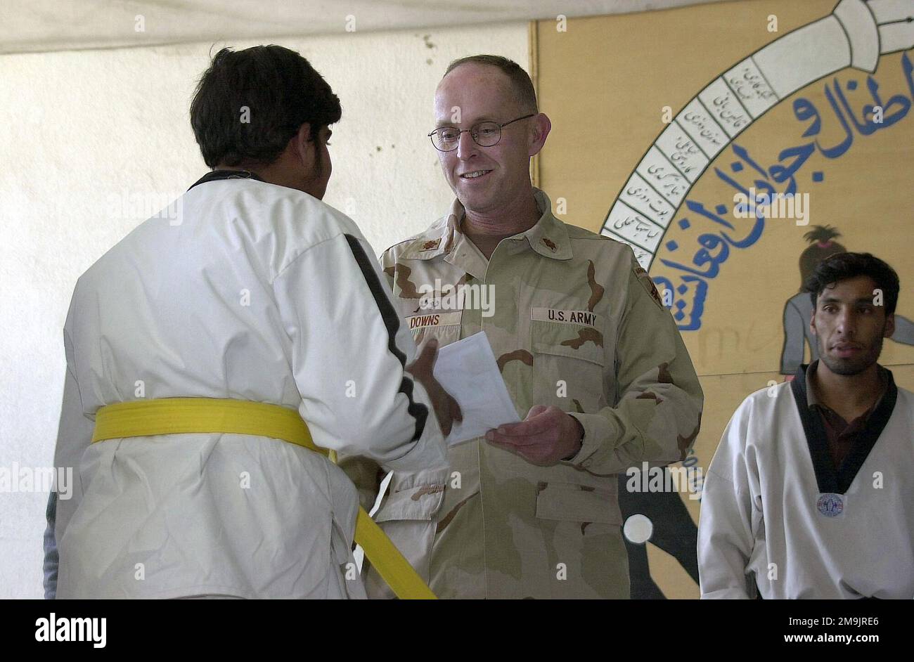 US Army (USA) Major (MAJ) Timothy Downs, presents a certificate to an ...