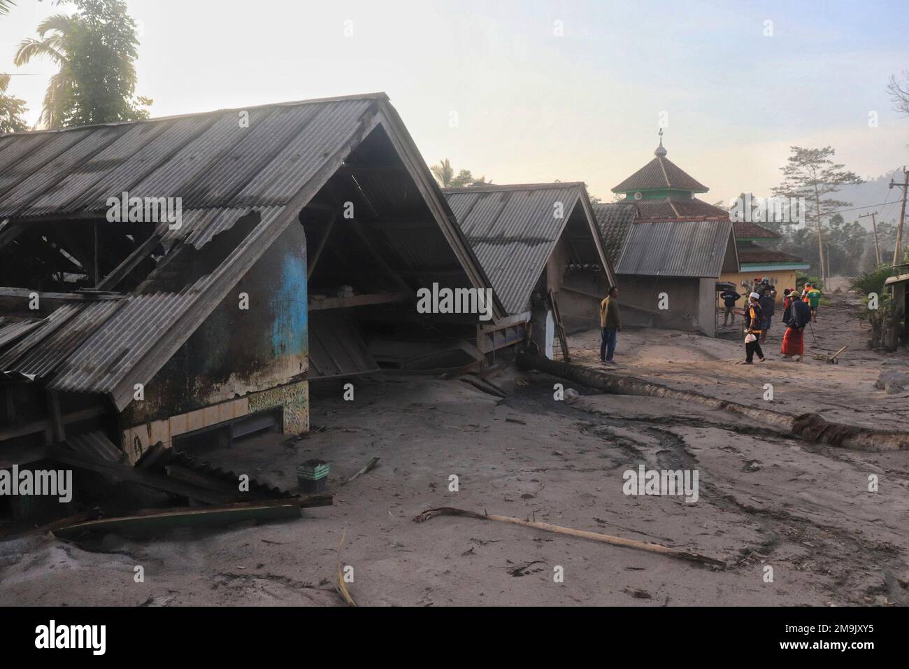 Villagers inspect the damage as houses are seen buried in volcanic ash ...