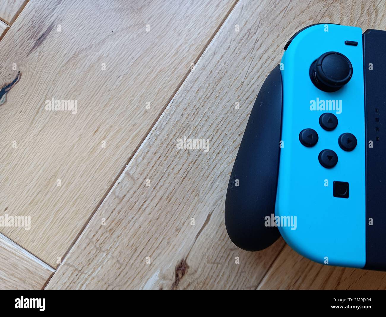 A Nintendo Switch controller blue left side on a wooden floor ...