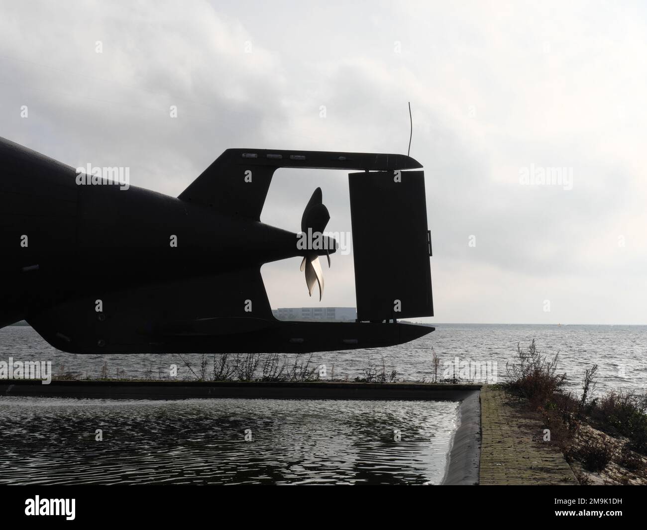 Rusty propeller and stern of old submarine with rudder in back light in ...