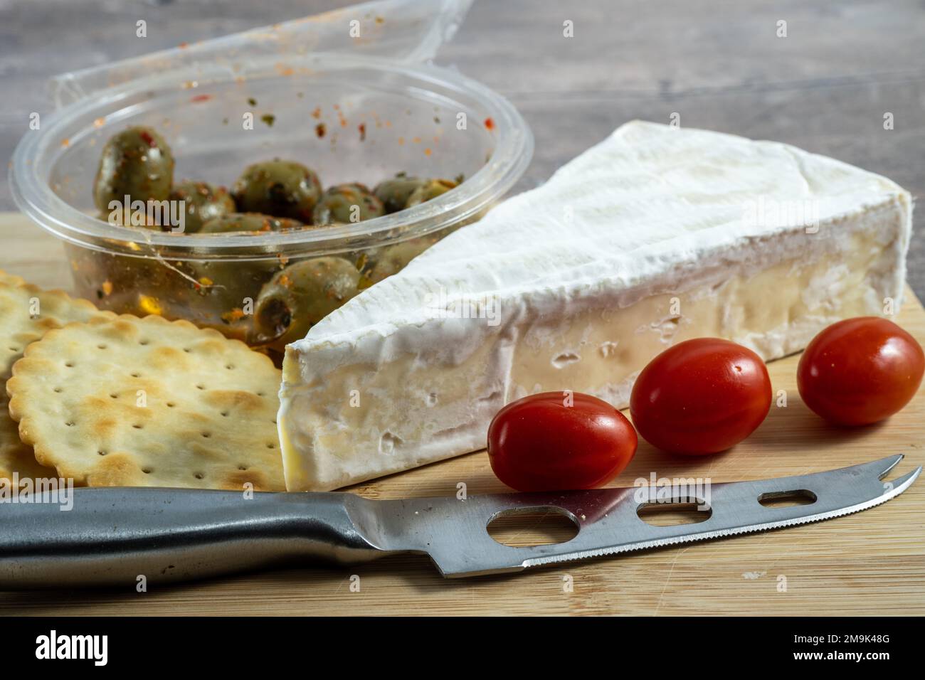 French Brie soft cheese served with pitted green olives red plum ...