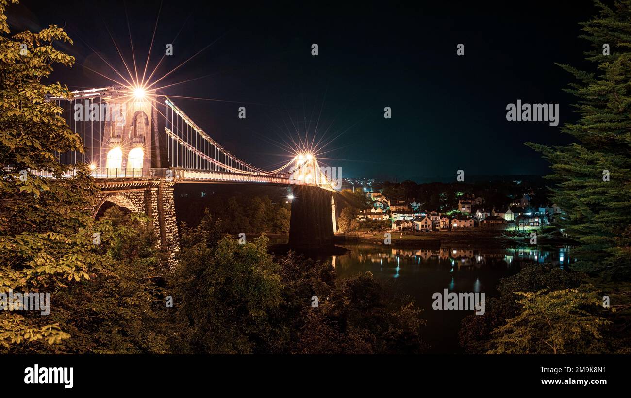 The Menai suspension bridge at night with lights on and reflections ...