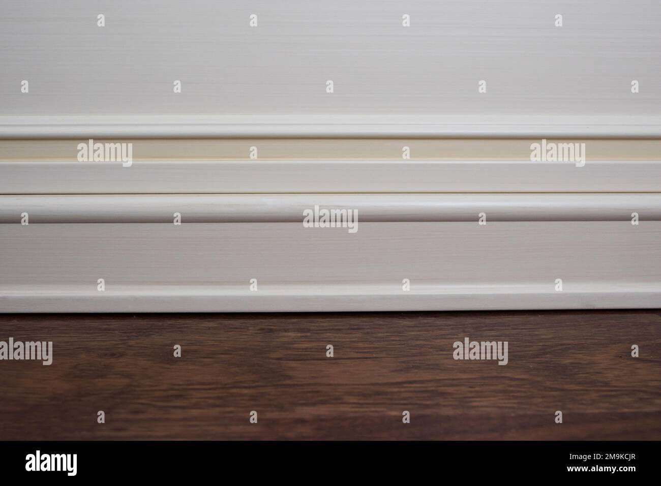 Matte wall, white baseboard and tiles immitating hardwood flooring ...