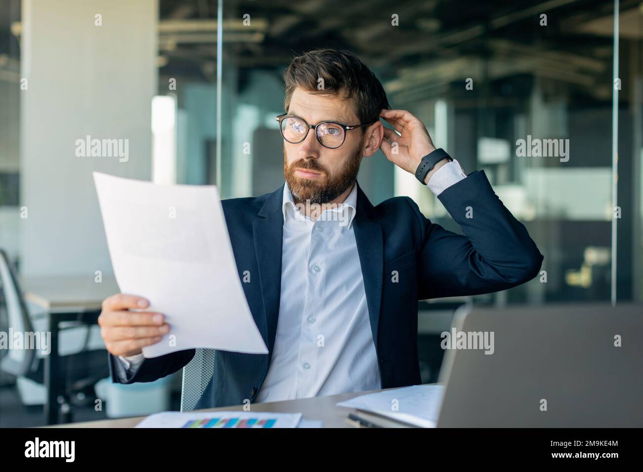 Middle aged male manager with documents checking marketing report ...