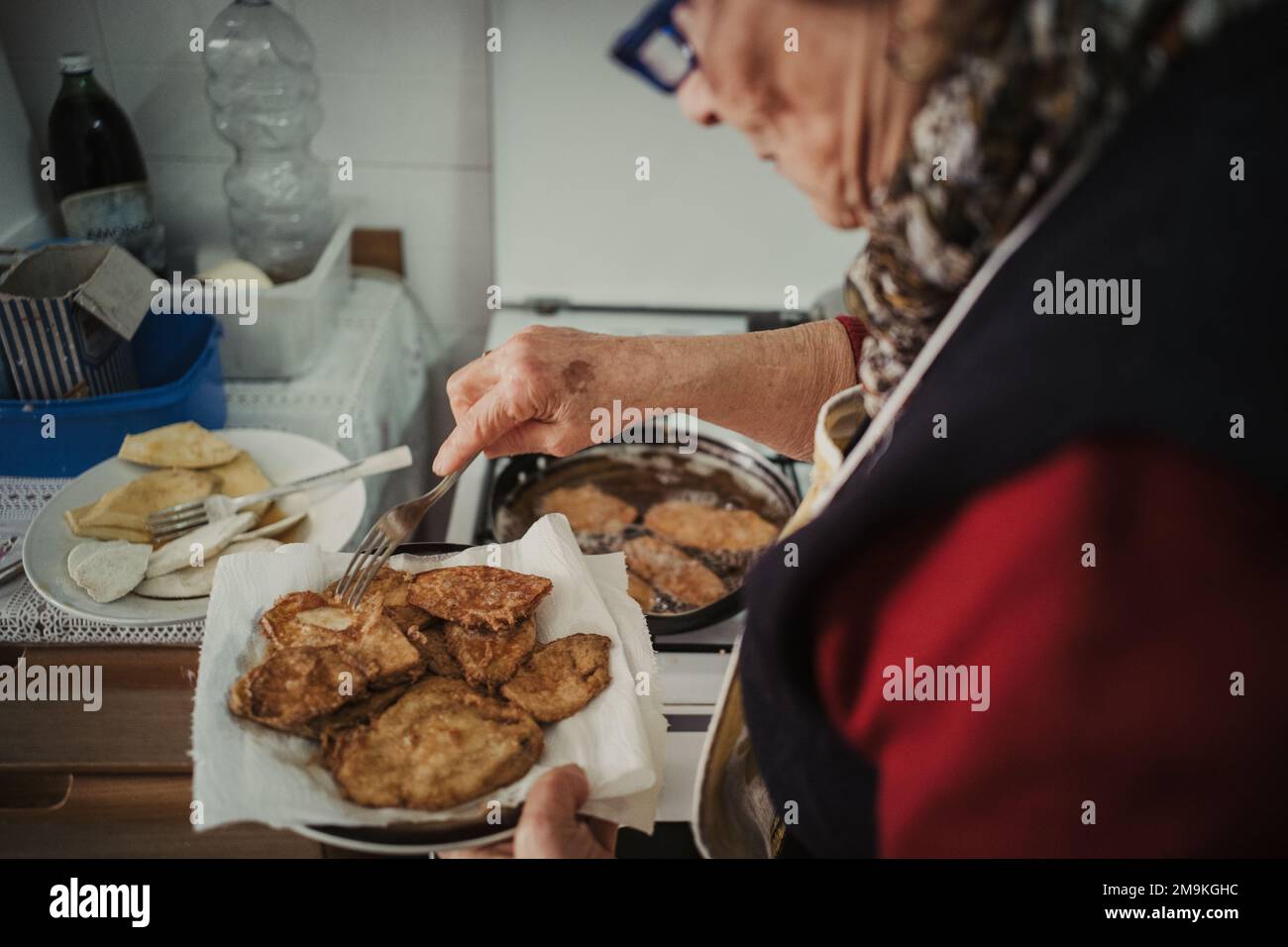 Grand mother cooking fried eggplants at home in a traditional setting ...
