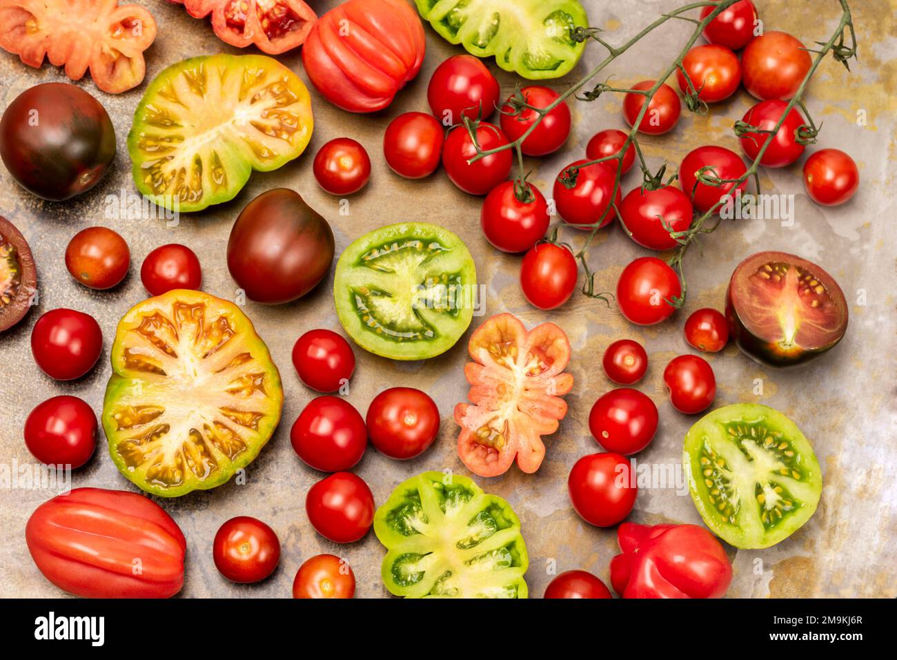 Chili tomato sprigs. Red, green and dark red tomatoes. Flat lay. Rusty ...