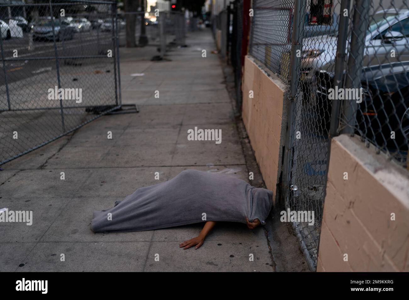 A mentally ill homeless woman wipes the surface of a sidewalk while ...