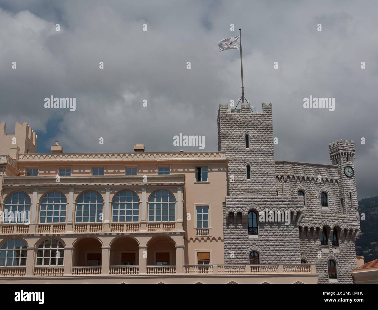 A low angle shot of a castle with a flag and a cloudy sky in Monaco ...