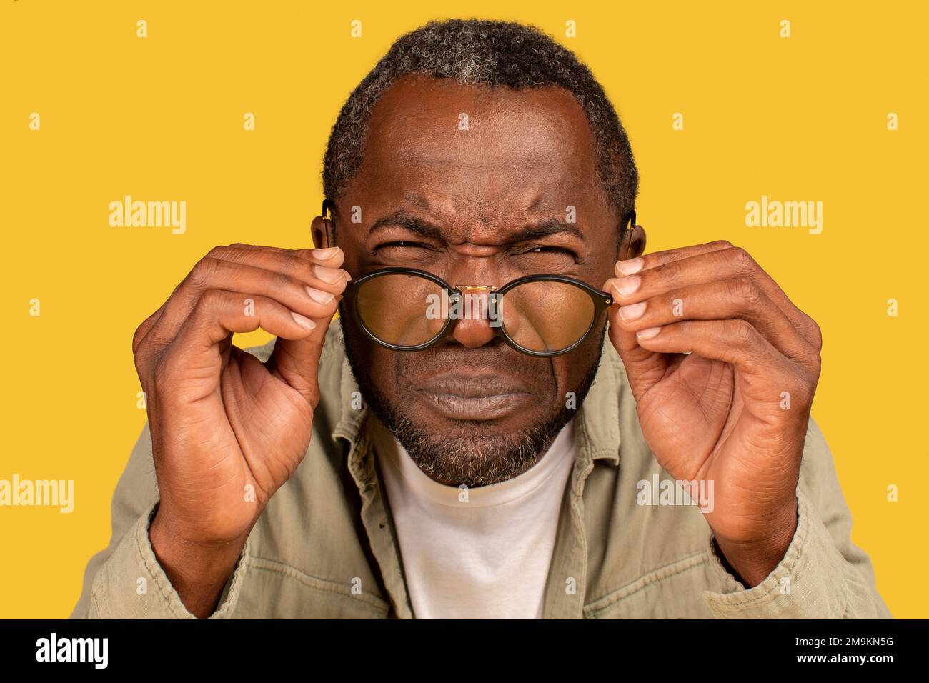 Concentrated african american middle aged man squinting eyes, takes off ...