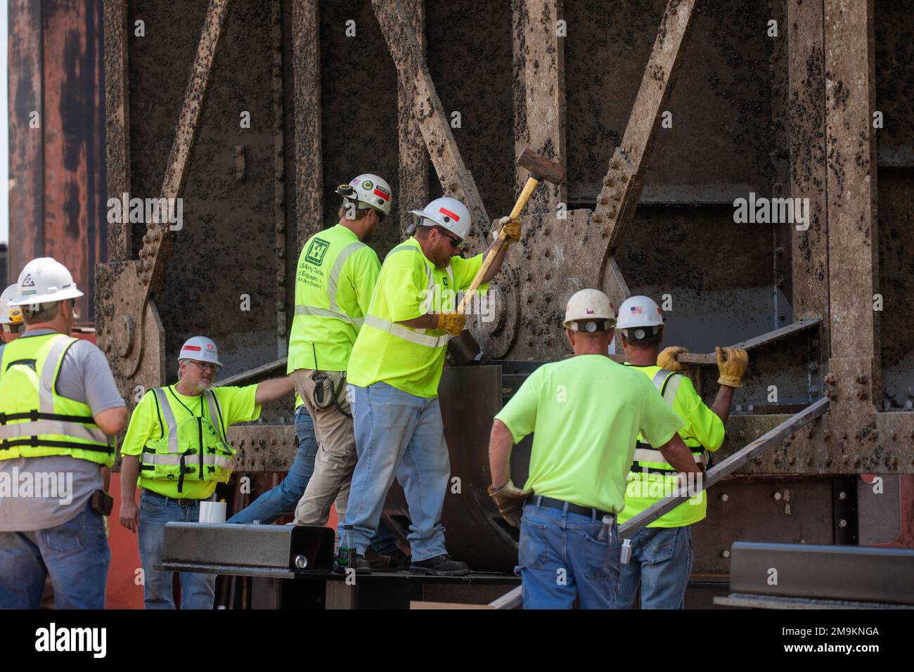 Maintenance crews diligently hammer shims into place so the rolling ...