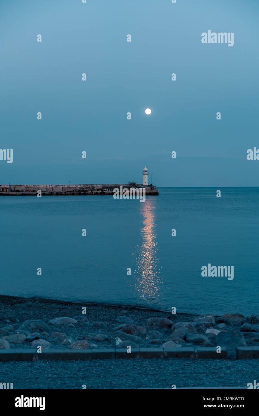 The full moon rises to the lighthouse, the moon path is not the sea ...