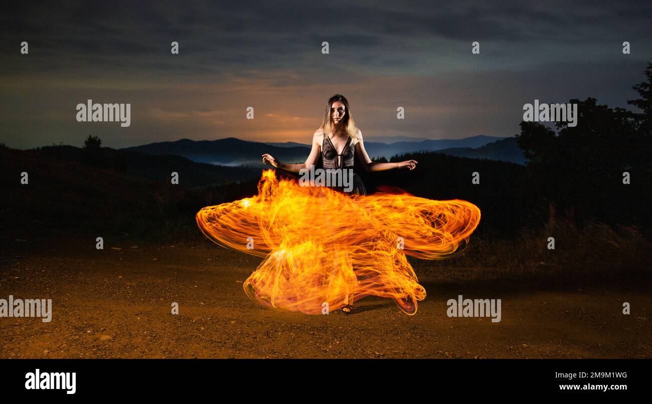 A beautiful shot of a young woman with long exposure lights looking ...