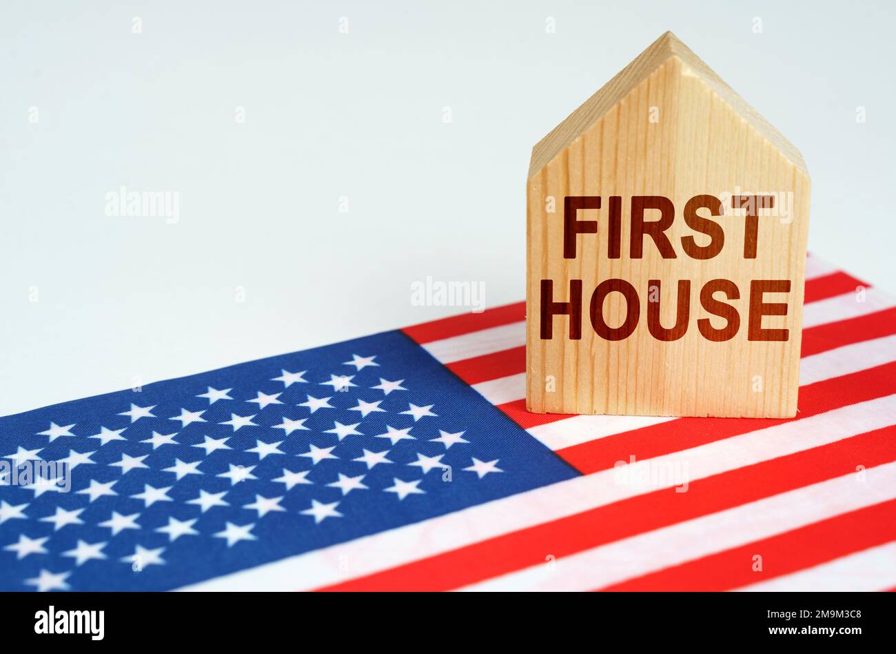 Real estate concept. On the US flag is a model of a wooden house with ...