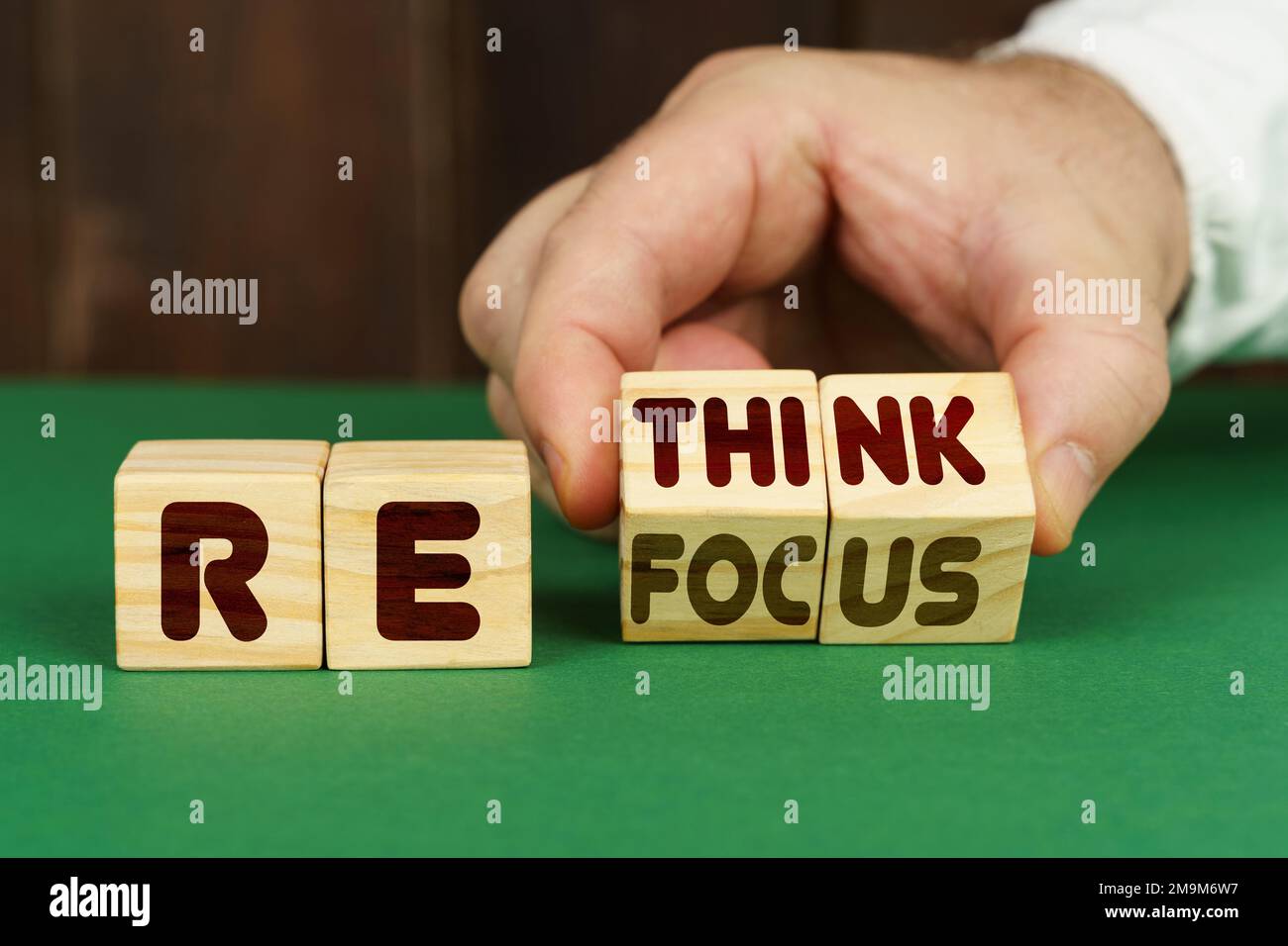 Business concept. On a green surface, a man puts cubes with the ...