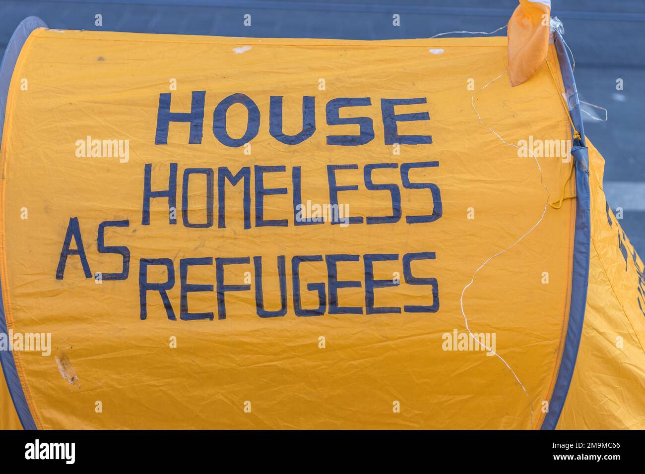 A text of "HOUSE HOMELESS AS REFUGEES" in black on a yellow sleeping ...