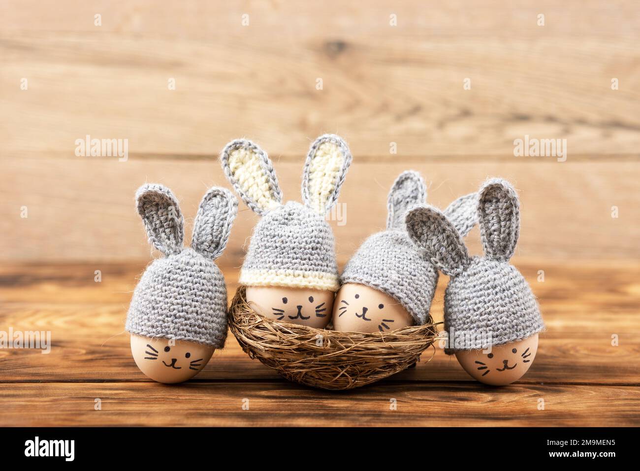 Four Easter eggs with funny faces and gray crocheted hats with bunny ...