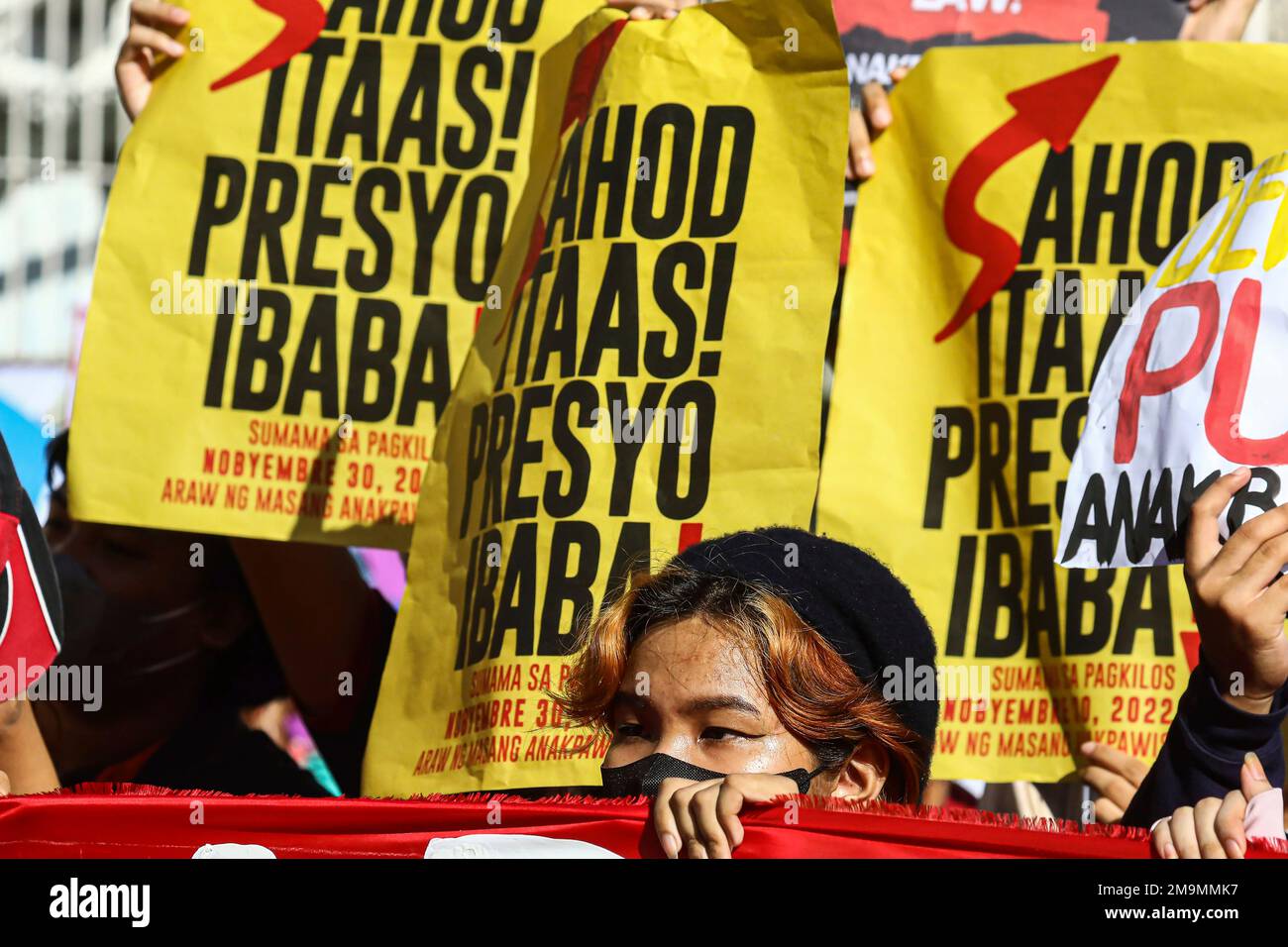 A protester behind signs calling for wage increase during a labor march ...