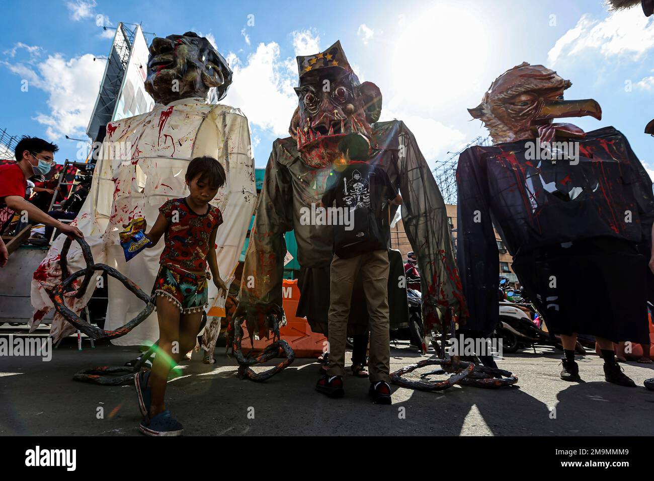 A girl passes by the protest effigies during a labor march on Bonifacio ...
