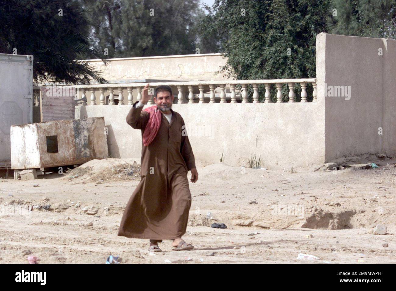 A local Iraqi man smiles and waves at passing coalition forces in the ...