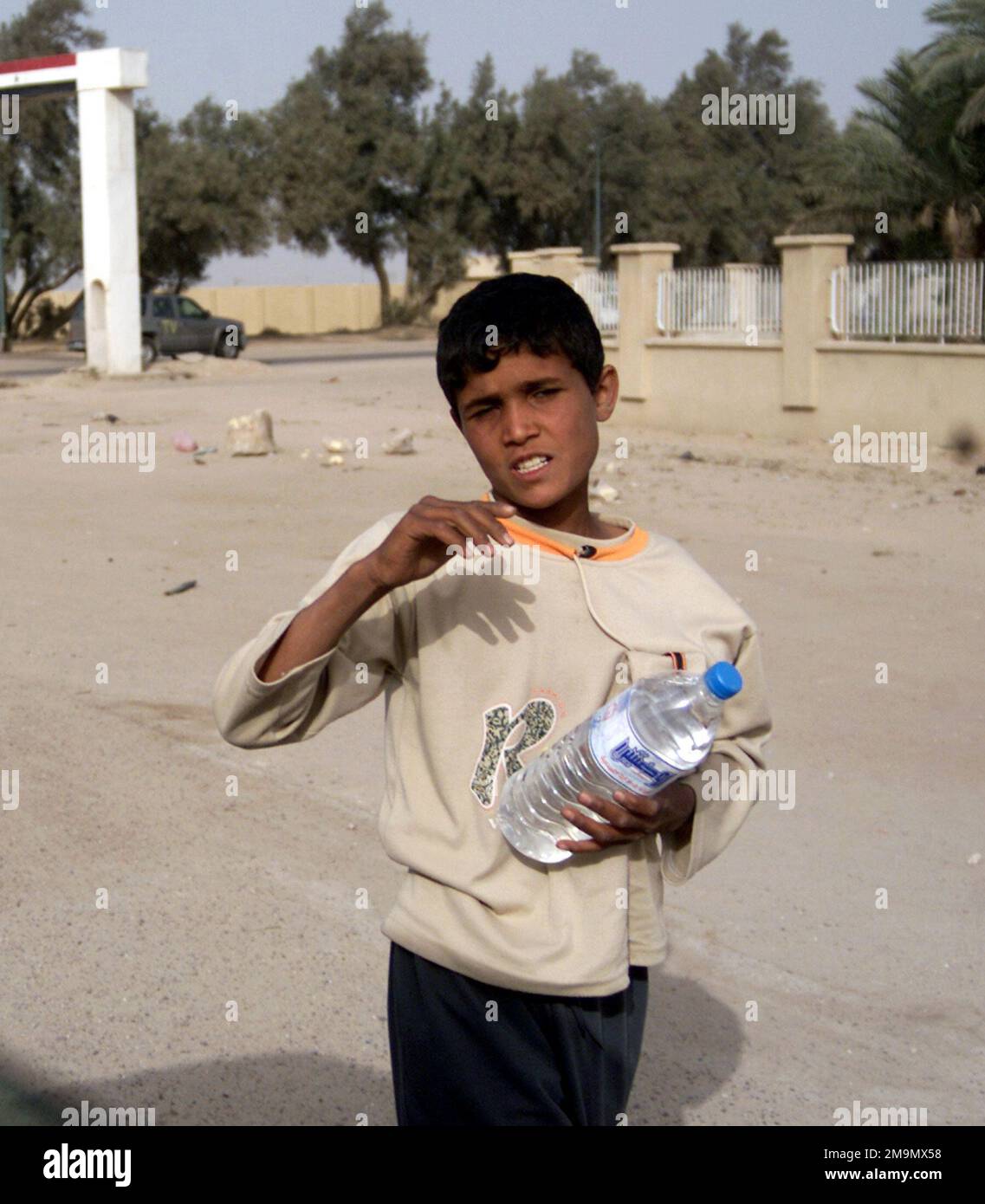 A local Iraqi boy carrying a bottle of water waves at passing coalition ...