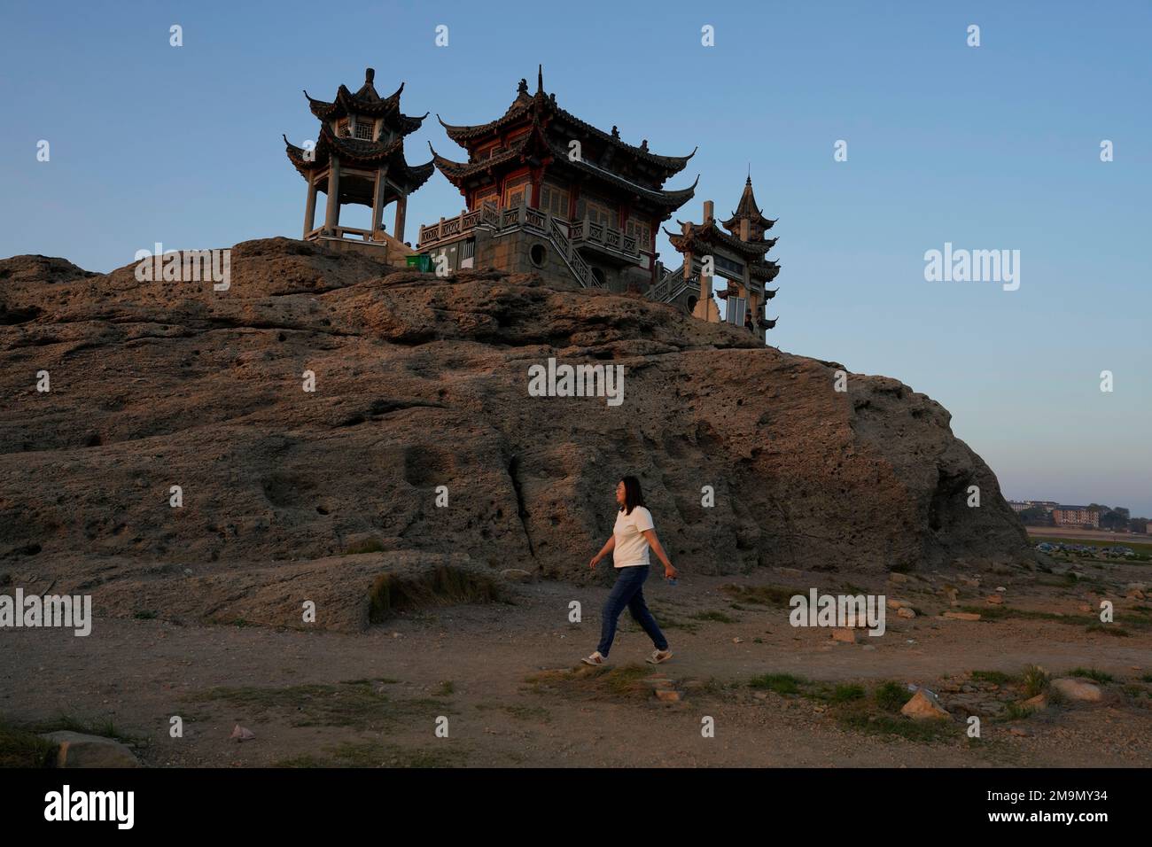 A woman walks past the base of Falling Star Mound that is normally ...