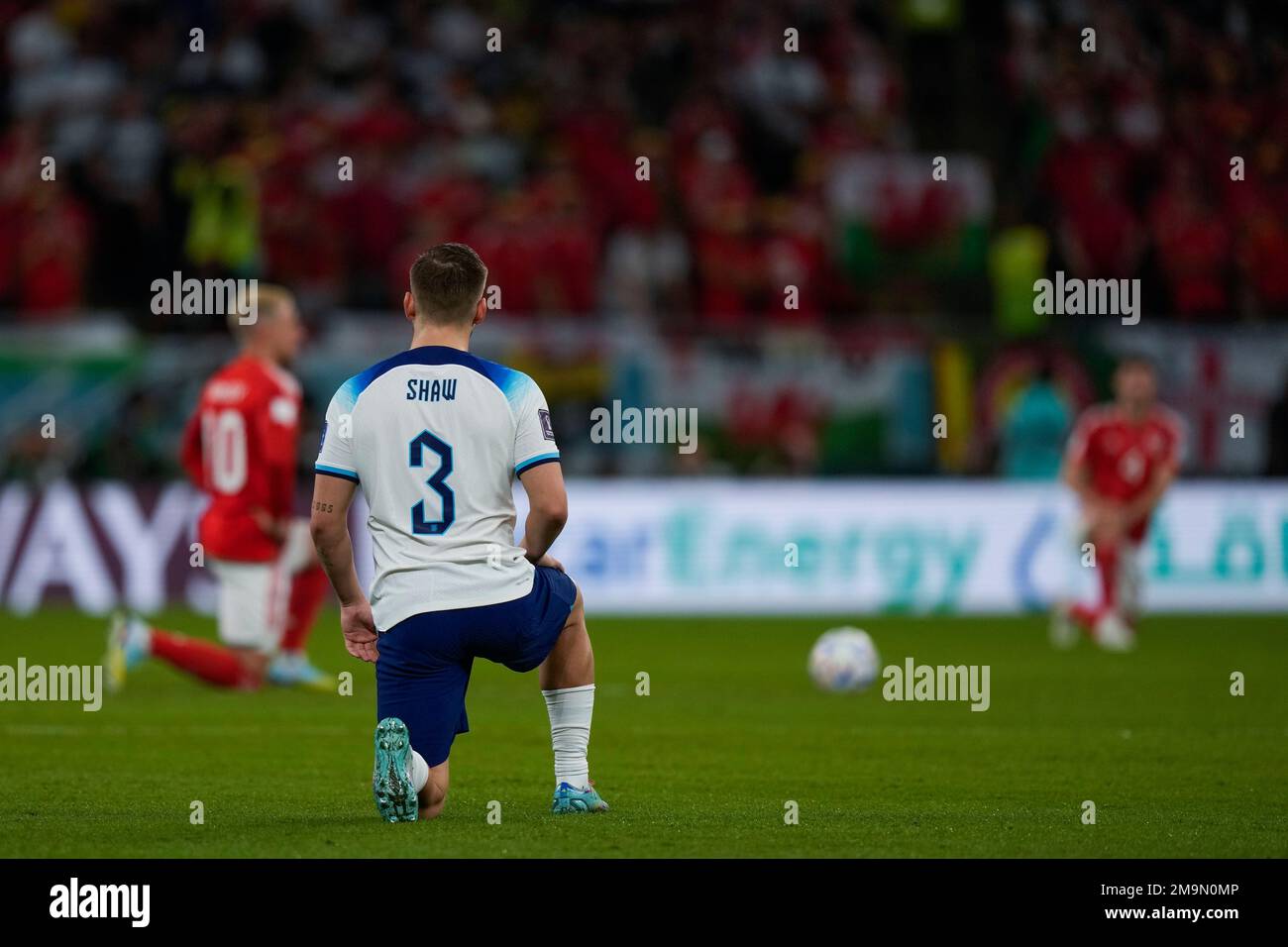 England's Luke Shaw knees along Wales players, background, just before ...
